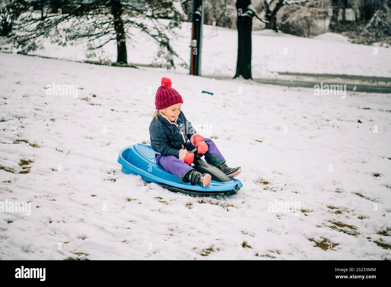 Smiling child sledding down a snowy hill with joy Stock Photo - Alamy