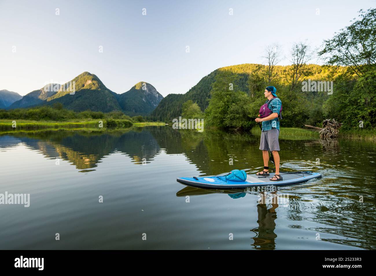 Man wearing lifejacket standing on paddle bpard Stock Photo - Alamy