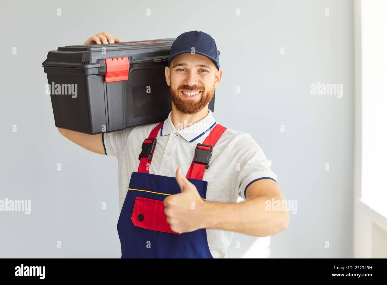Repairman holding tool box in hands in empty room looking cheerful at ...