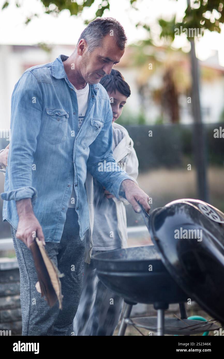 Father and son bonding over a backyard barbecue vertical Stock Photo ...