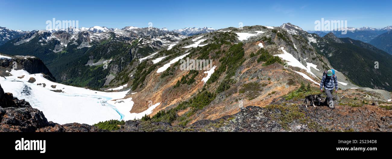 Solo hiker treks along rocky mountain ridge top with dog Stock Photo ...