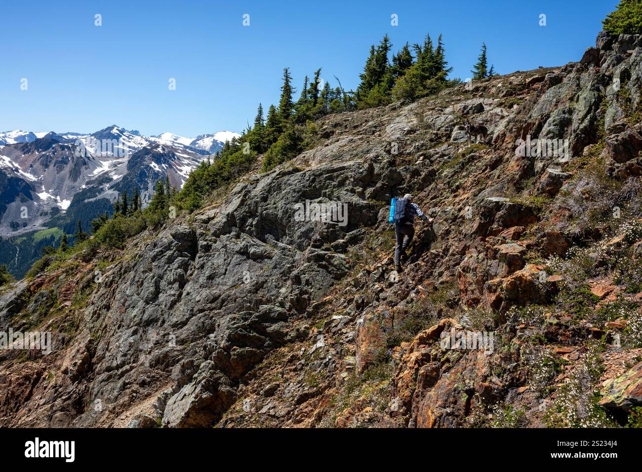Backpacker Exploring Rugged Mountain Terrain with Snow-Capped Peaks ...