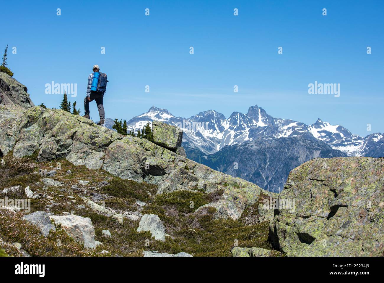 Backpacker Exploring Rugged Mountain Terrain with Snow-Capped Peaks ...