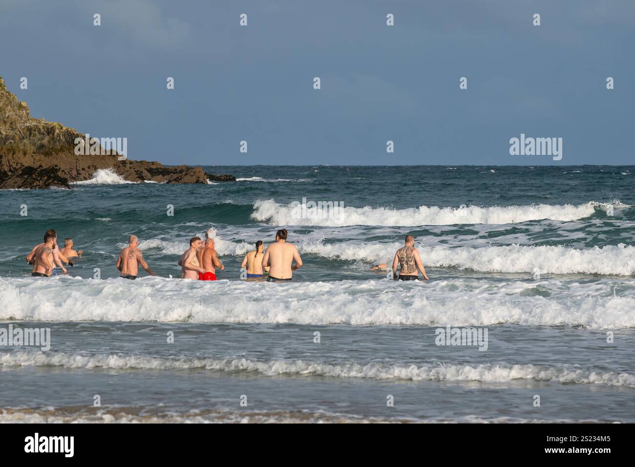 A group of male cold water swimmers wading into the sea for an early ...