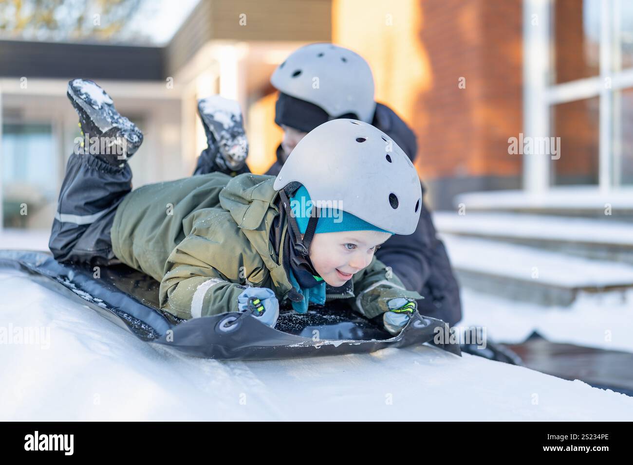 Child sledding face-first in the snow, wearing a helmet Stock Photo - Alamy