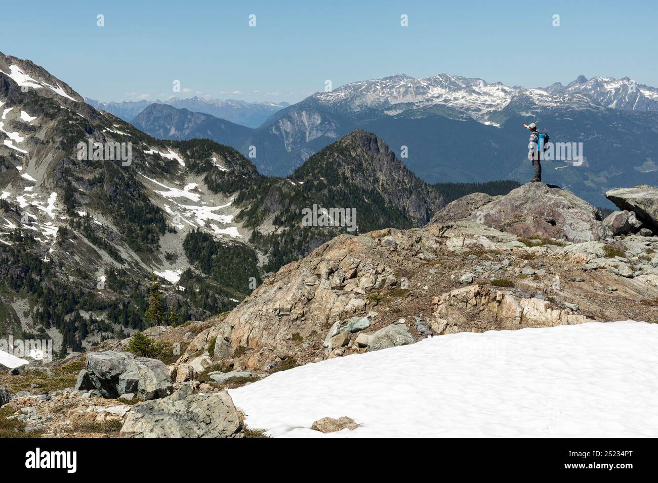 Solo man explores rugged mountain terrain with Snow-Capped Peaks Stock ...
