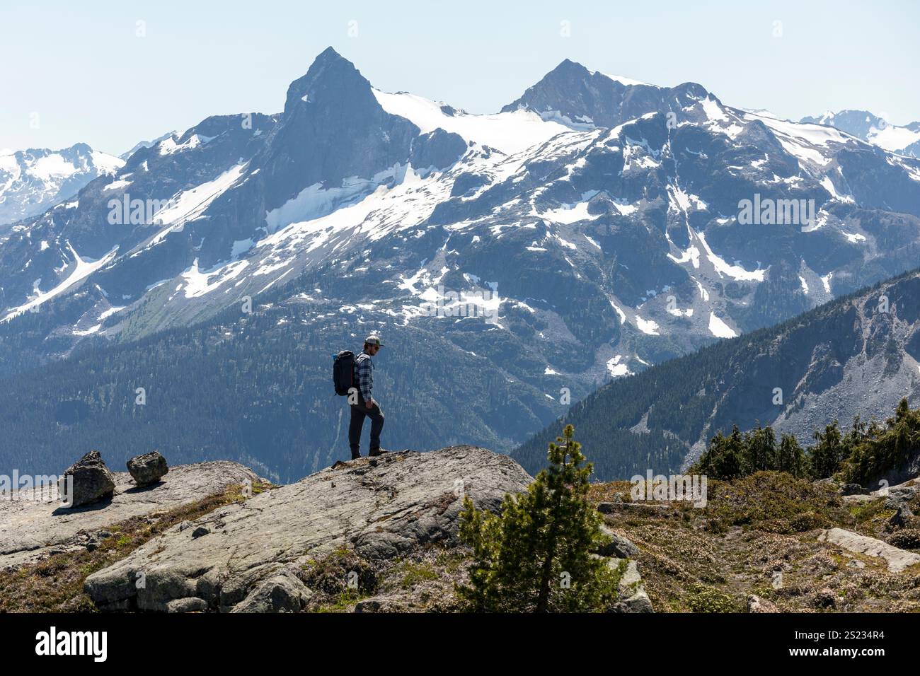 Solo man hiking in rugged mountain terrain with Snow-Capped Peaks Stock ...