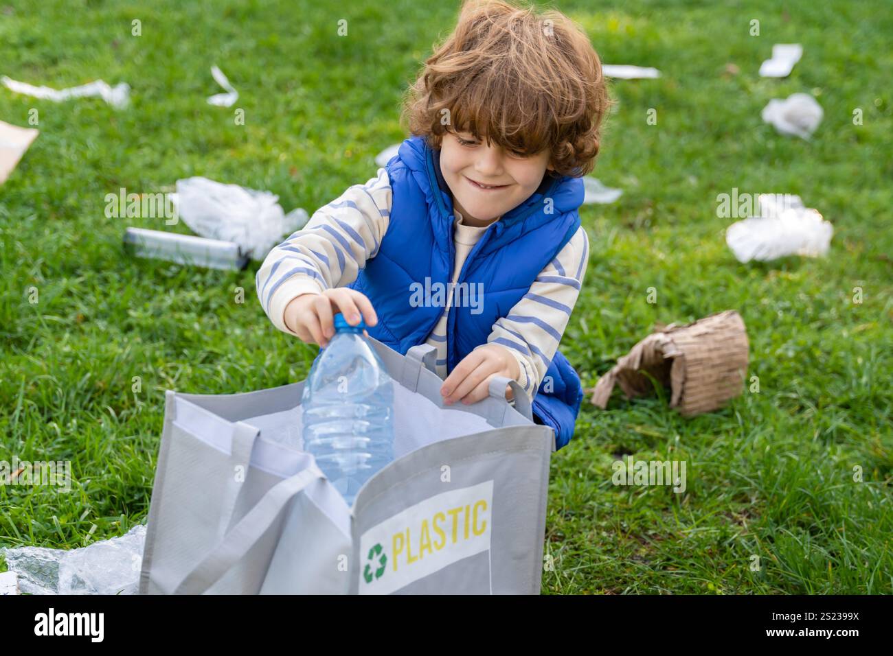Caucasian male kid outdoors collecting plastic waste during community ...