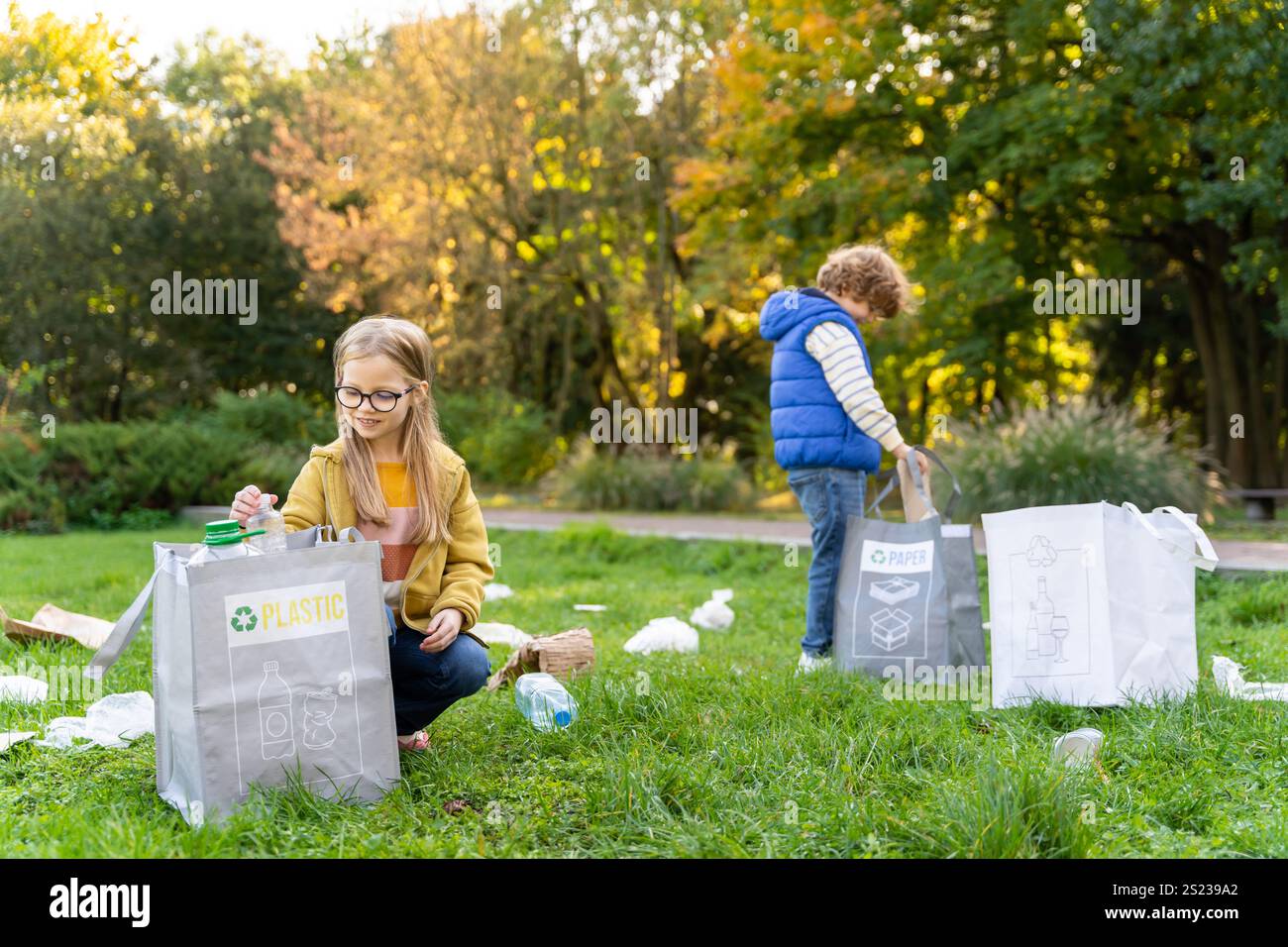 Small children picking up trash together sorting plastic waste into ...