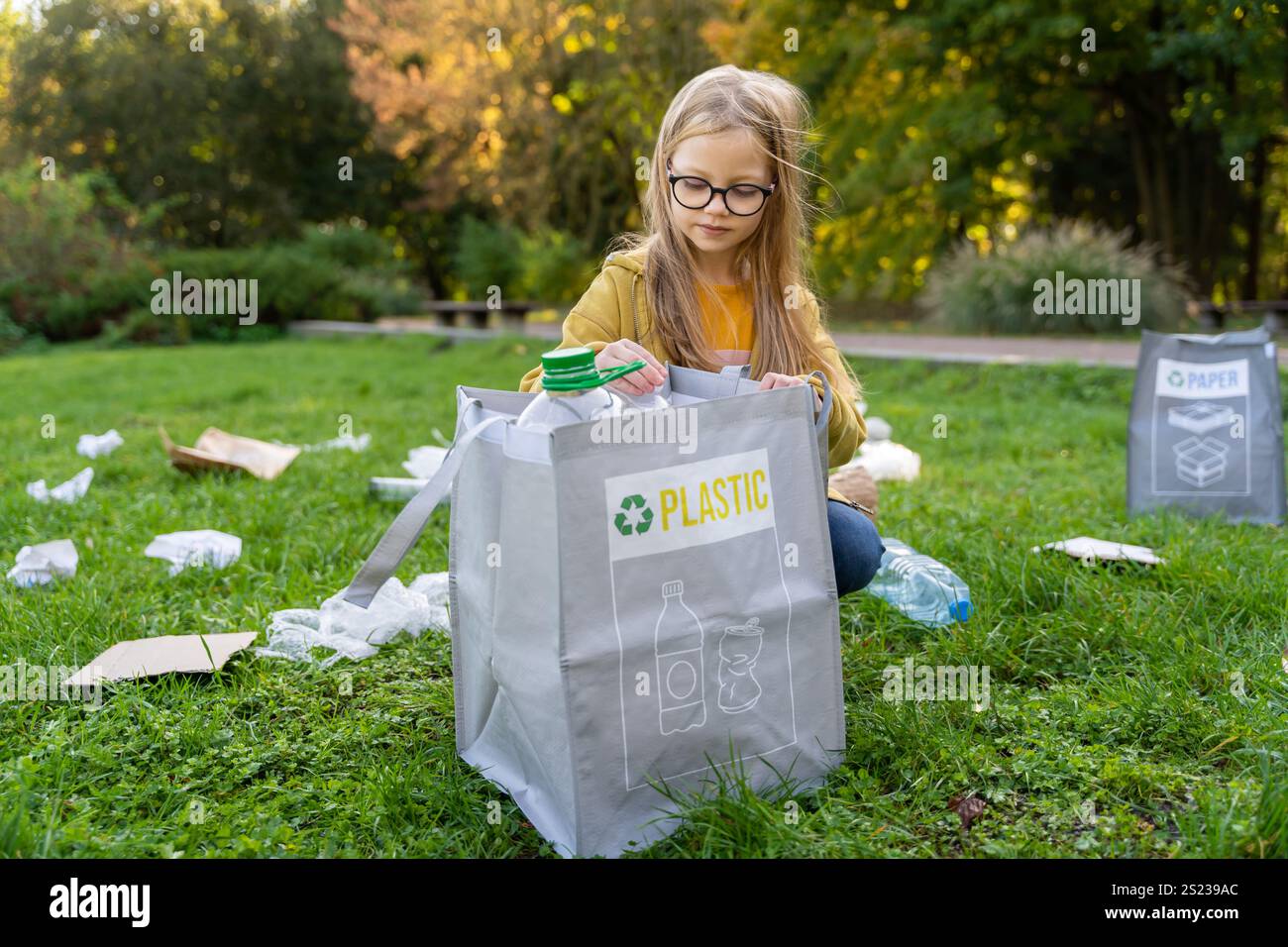 Little girl collecting garbage in park to recycle waste and reduce ...
