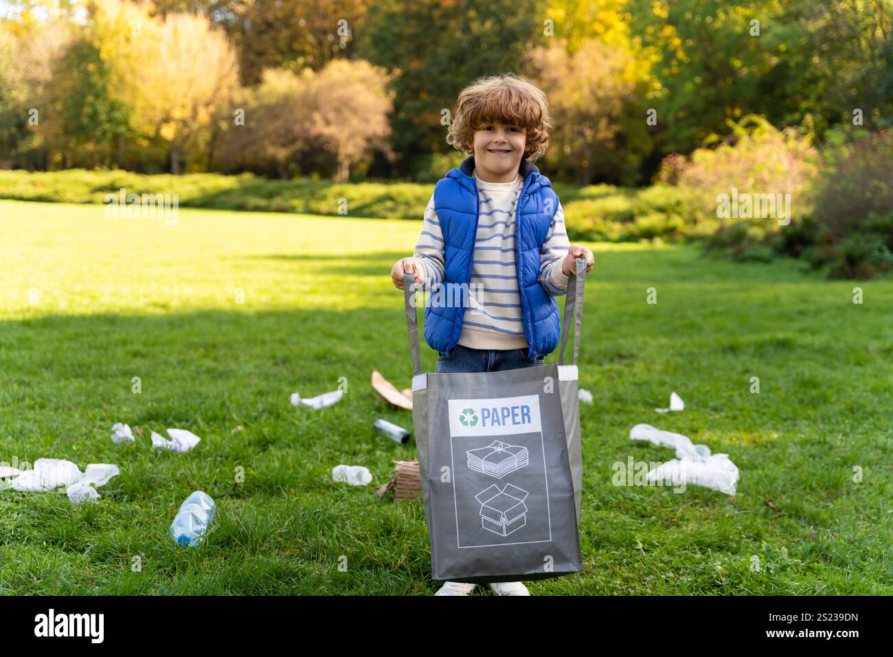 Male child cleaning trash in park participating in social project to ...