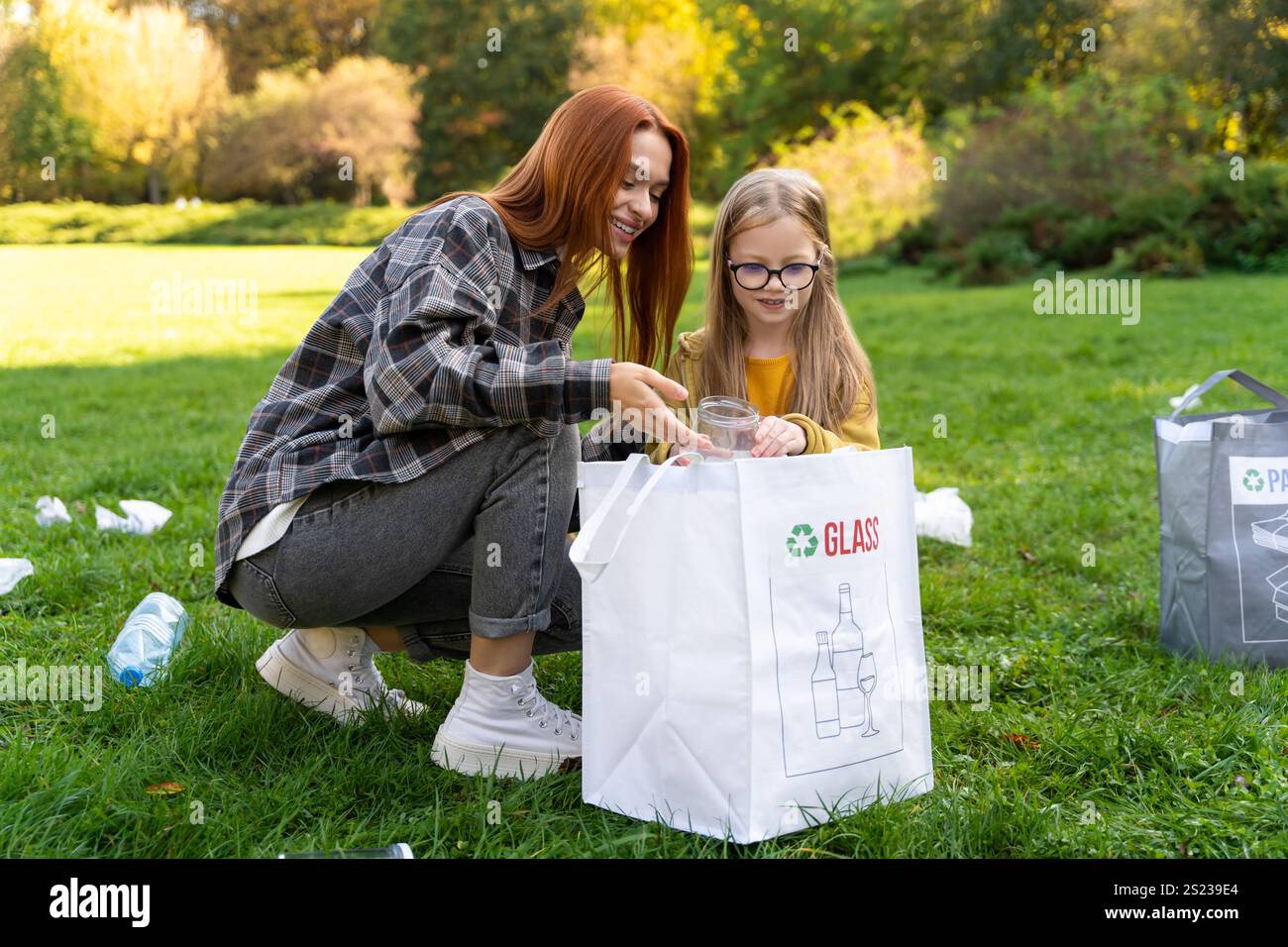 Small child picking up trash in park together with teacher sorting ...