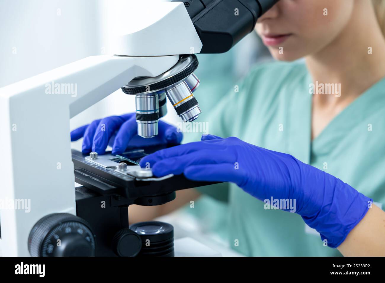 Medical woman in laboratory studying samples under microscope with ...