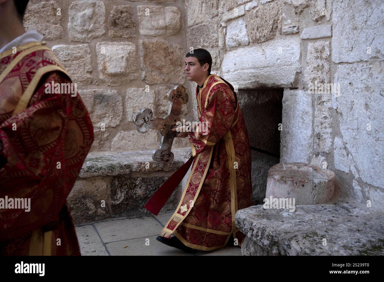A Greek Orthodox altar boy carries a cross out of the Church of the ...