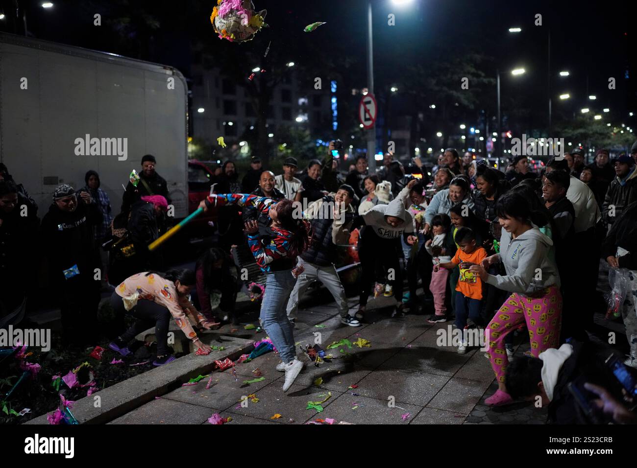 A woman strikes a traditional "pinata" donated by volunteers known as ...