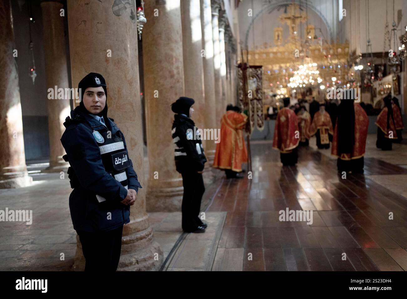 A Palestinian police woman stands guard as Greek Orthodox clergy gather ...