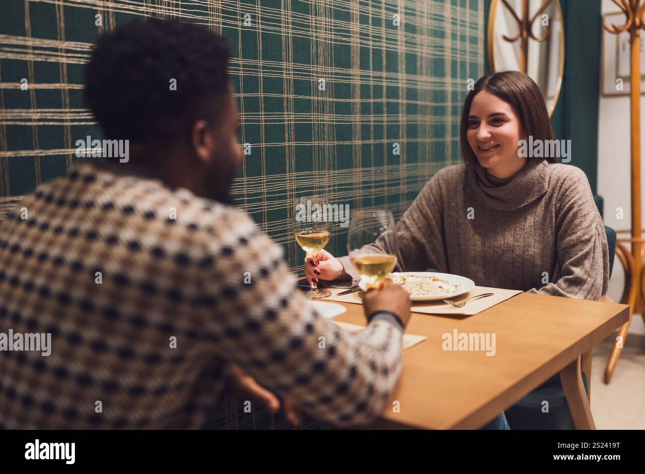 Two friends are having dinner at restaurant. They are sitting, talking ...