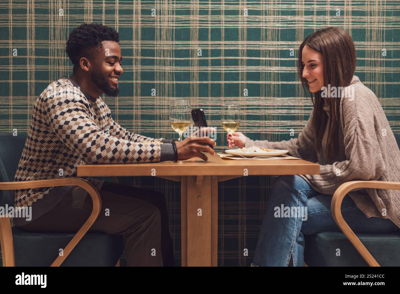 Two friends are having dinner at restaurant. They are sitting, talking ...