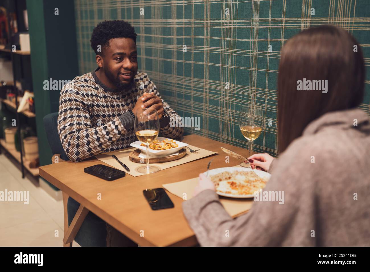 Two friends are having dinner at restaurant. They are sitting, talking ...