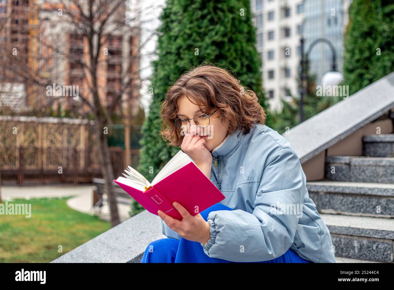 Girl reading a book on the street close-up. Teenage girl reading a book ...