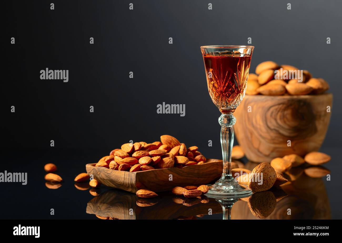 Strong alcoholic Italian liqueur Amaretto with almonds nuts on a black ...
