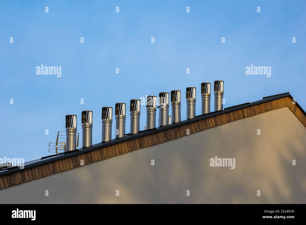 Rows of metal chimneys stand tall atop a factory building against a ...