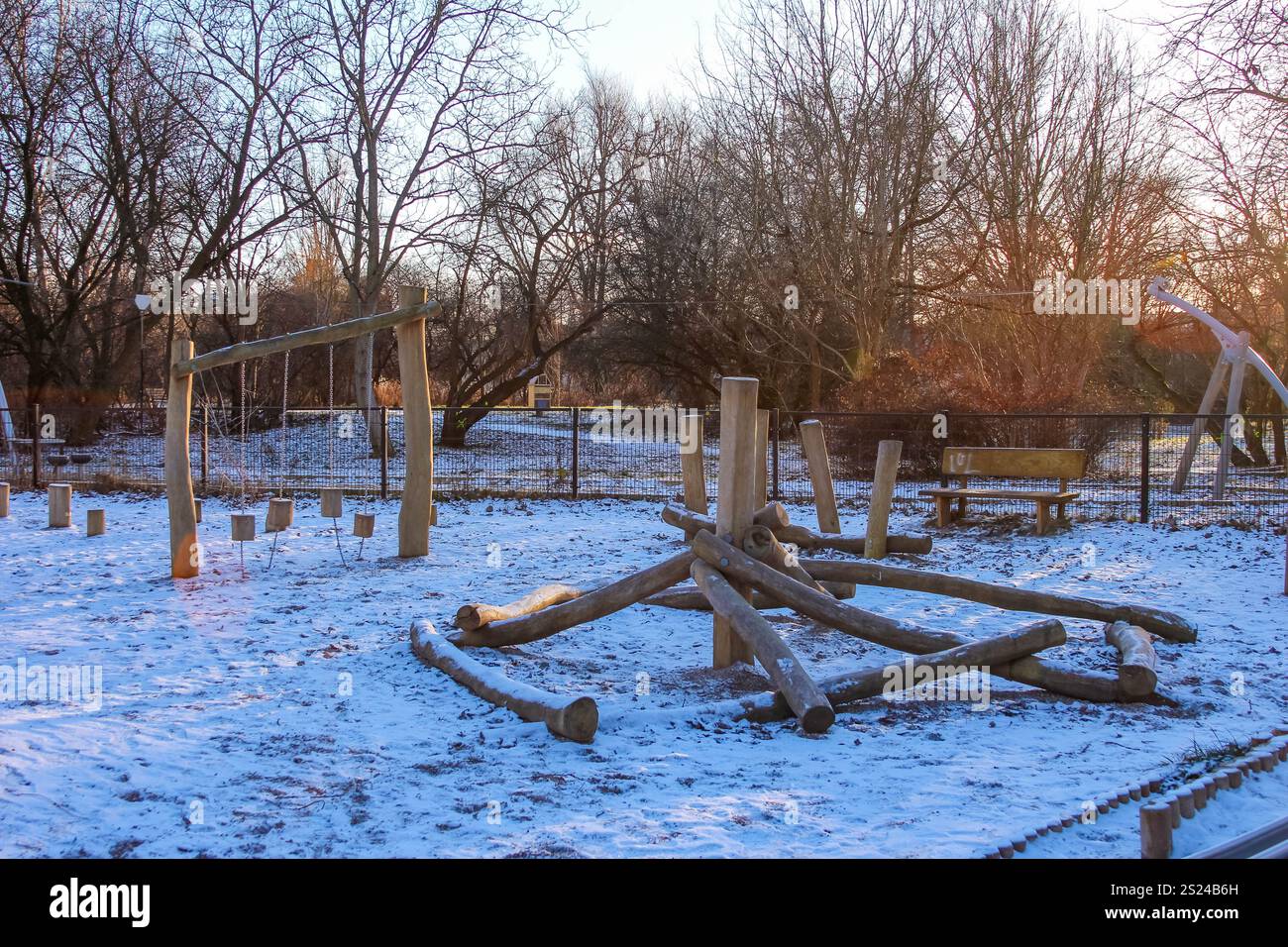 A playground blanketed in snow features wooden swings and play ...