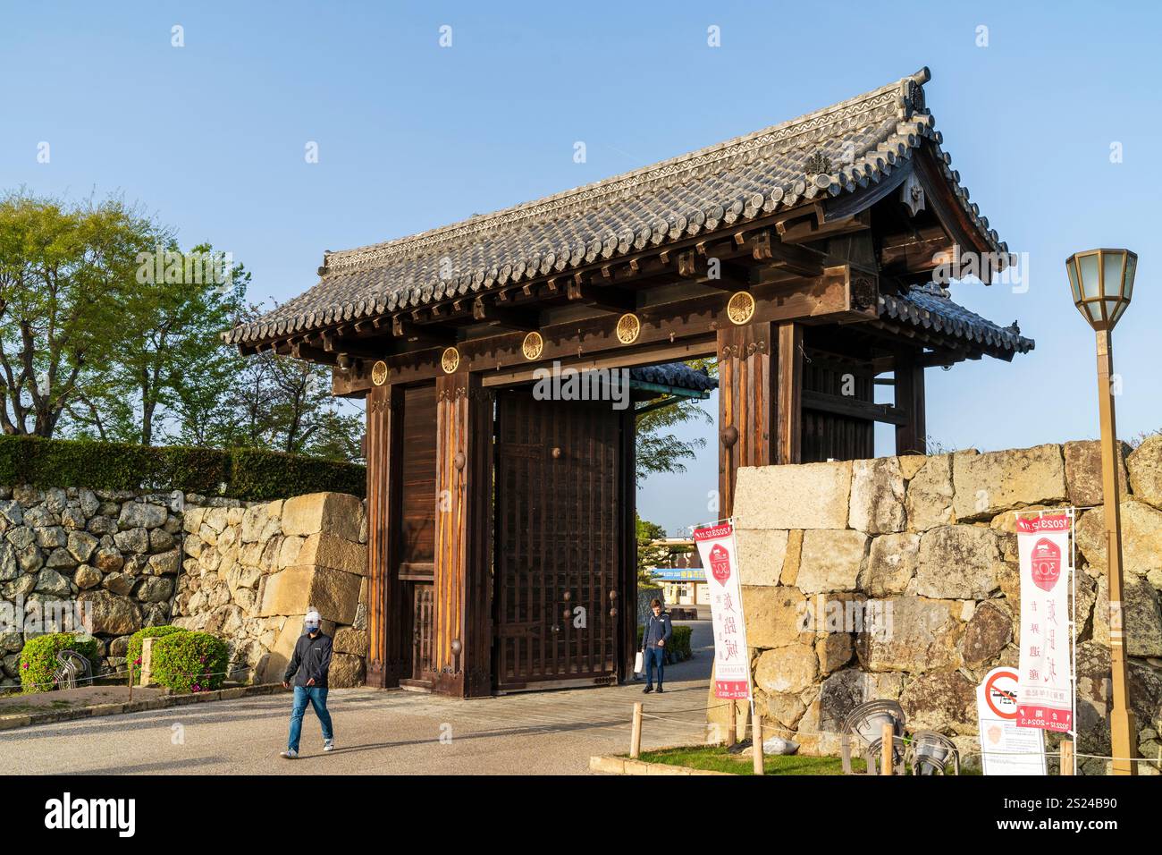 Two people walking through the Ote Mon, front gate of Himeji castle. A ...