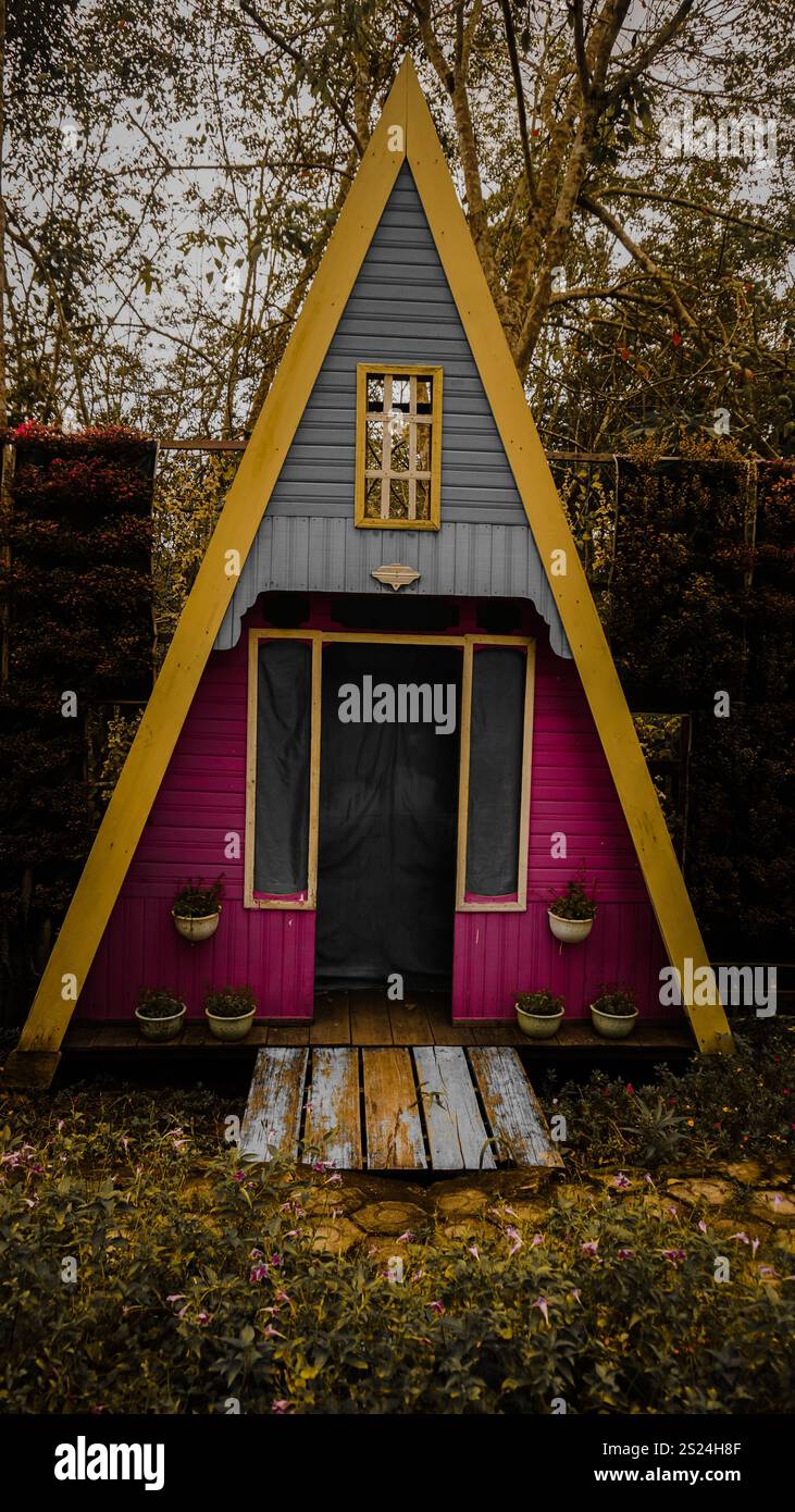 A small, colorful A-frame playhouse with a pink and blue facade ...