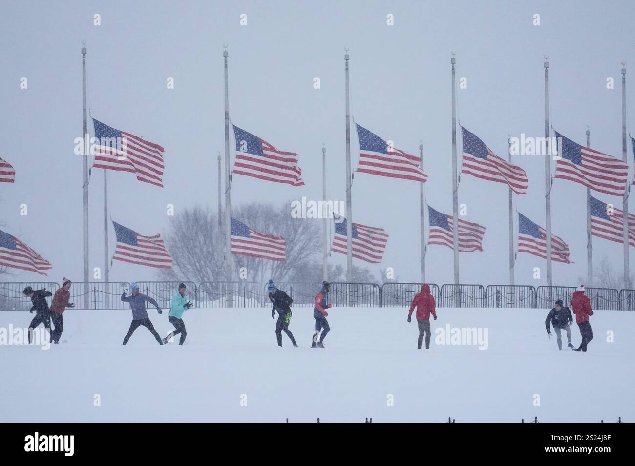 People engage in a snowball fight as U.S. flags, along the base of the ...