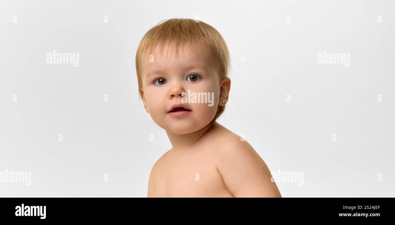 Close-up portrait of a toddler girl, baby face with a curious and ...