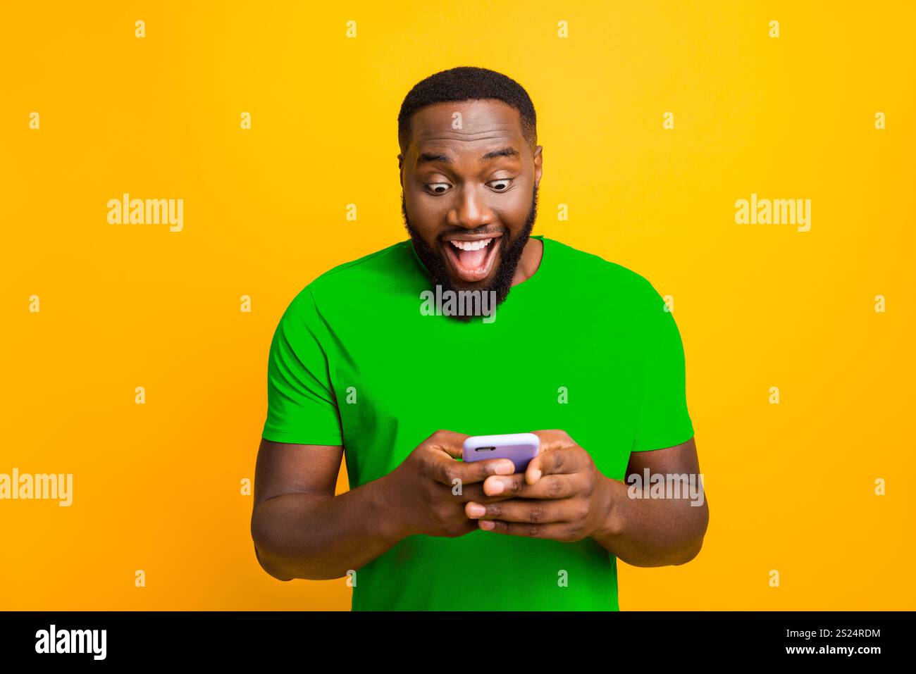 Photo of impressed black man watching something delightful on his phone ...