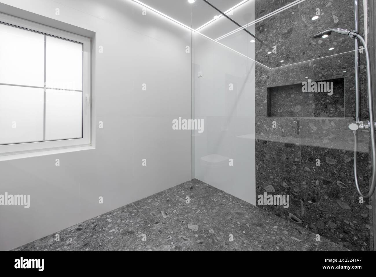 Contemporary bathroom design featuring sleek grey tiles, a glass shower ...