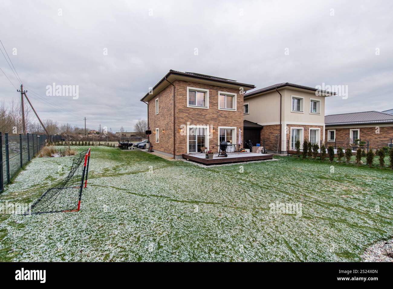 A brick house with a patio and a driveway. The house is surrounded by a ...