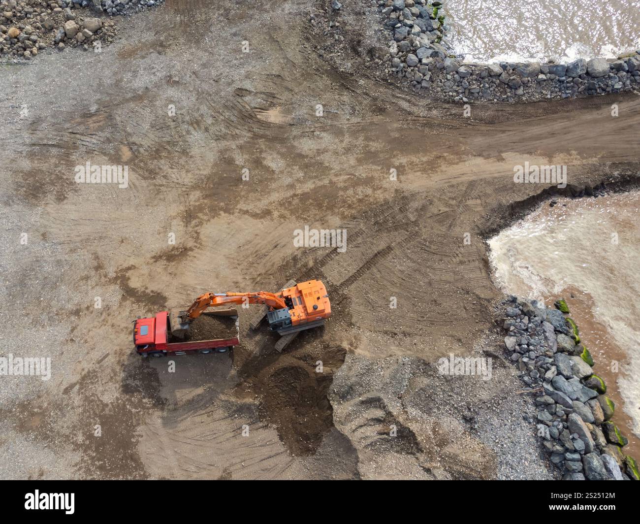 Aerial view of an excavator loading sand into a truck, top view ...