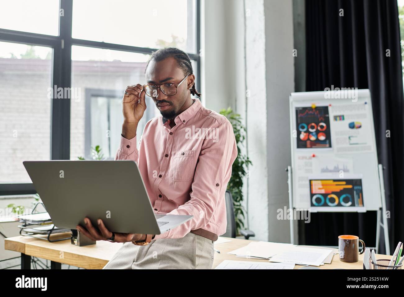 A young African American man focuses on his laptop, brainstorming ideas ...