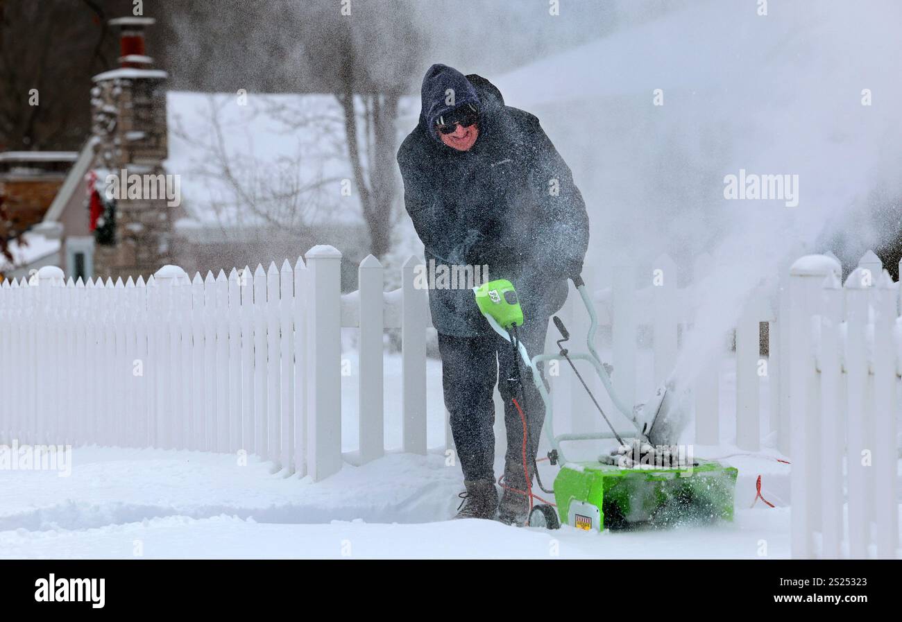 Dave Thomasson uses an electric snowblower to clear his driveway in the ...