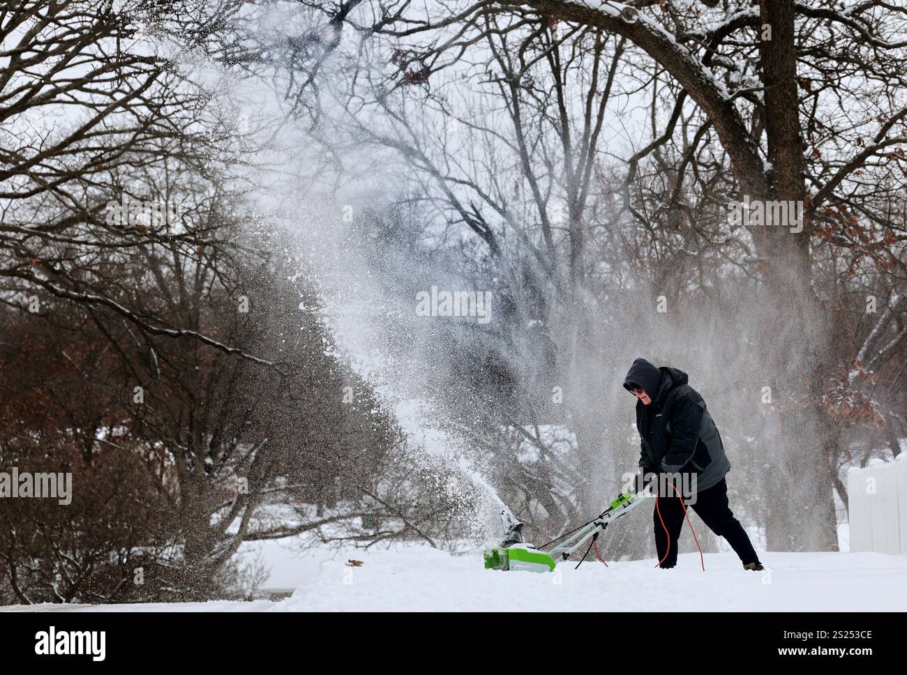 Dave Thomasson uses an electric snowblower to clear his driveway in the ...