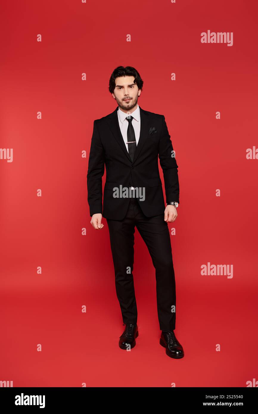 A young handsome man stands tall in a polished black suit, exuding ...