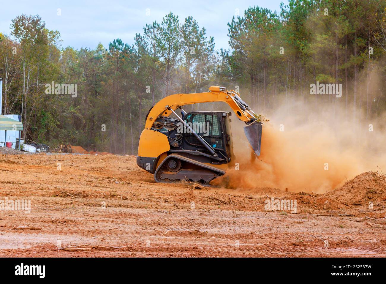 Construction vehicle prepares plot of land by moving dirt amid dust ...