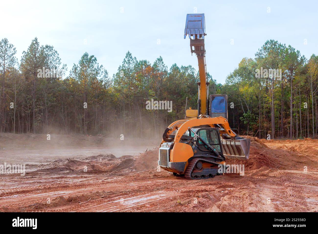 Tracked loader operates on construction site, moving dirt with raised ...