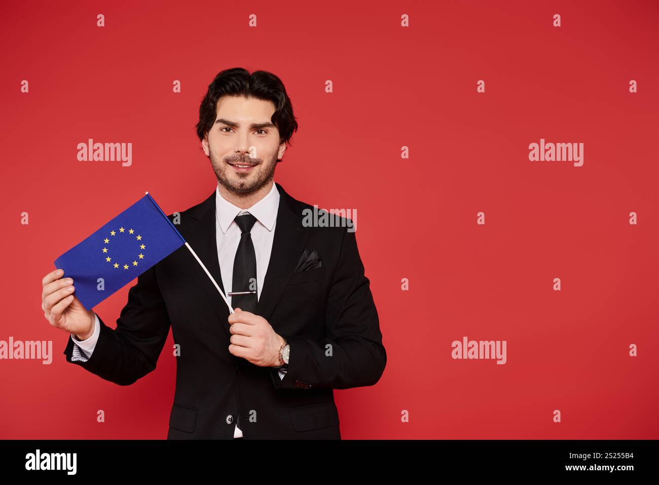 Young man dressed in formal attire displays the EU flag with a ...