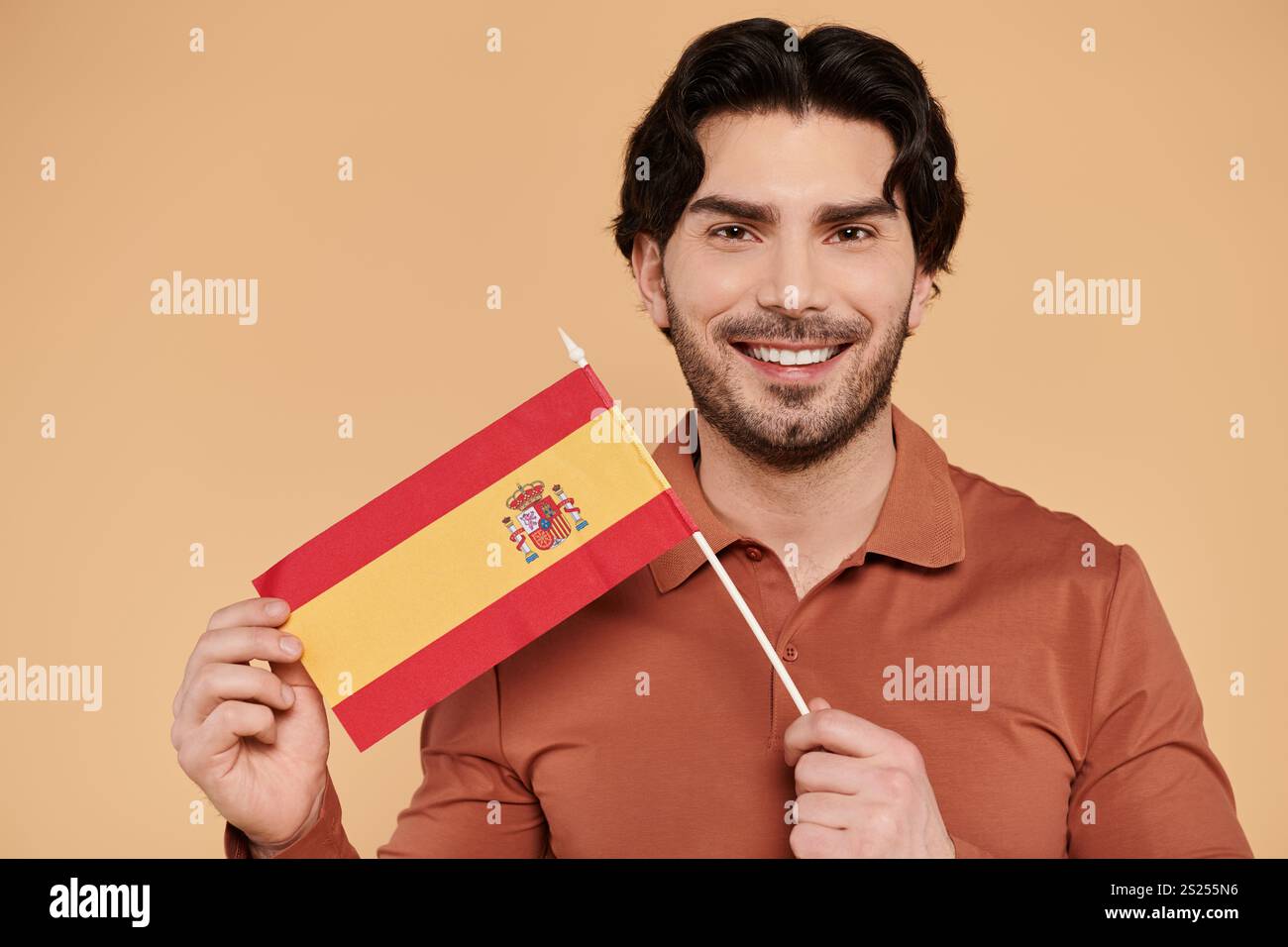 A young handsome man beams with pride as he holds a Spanish flag ...