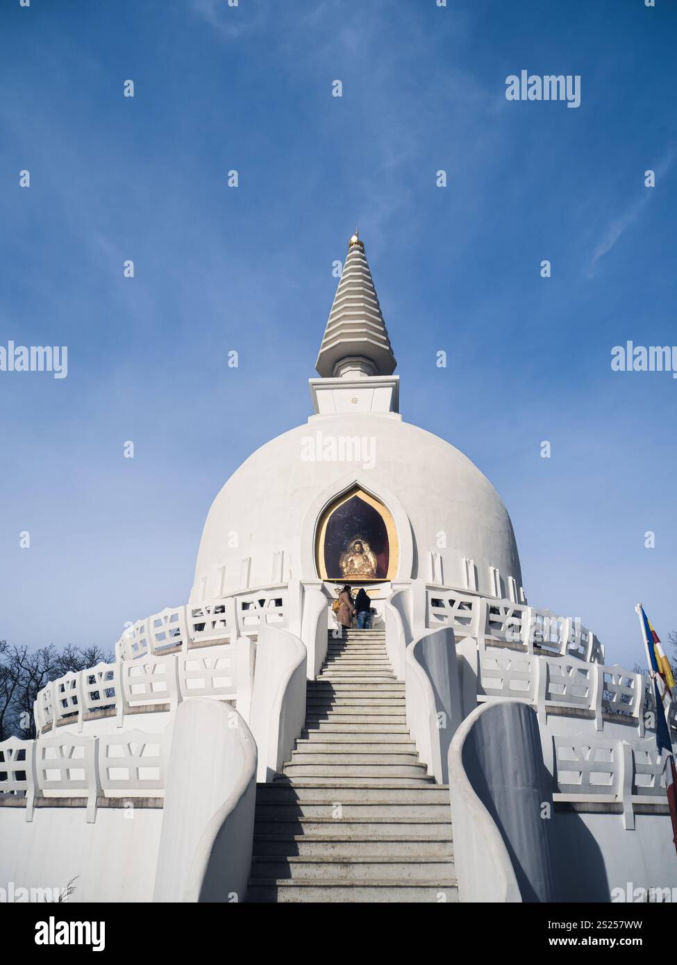 A pristine white Buddhist stupa with a golden Buddha statue at its ...