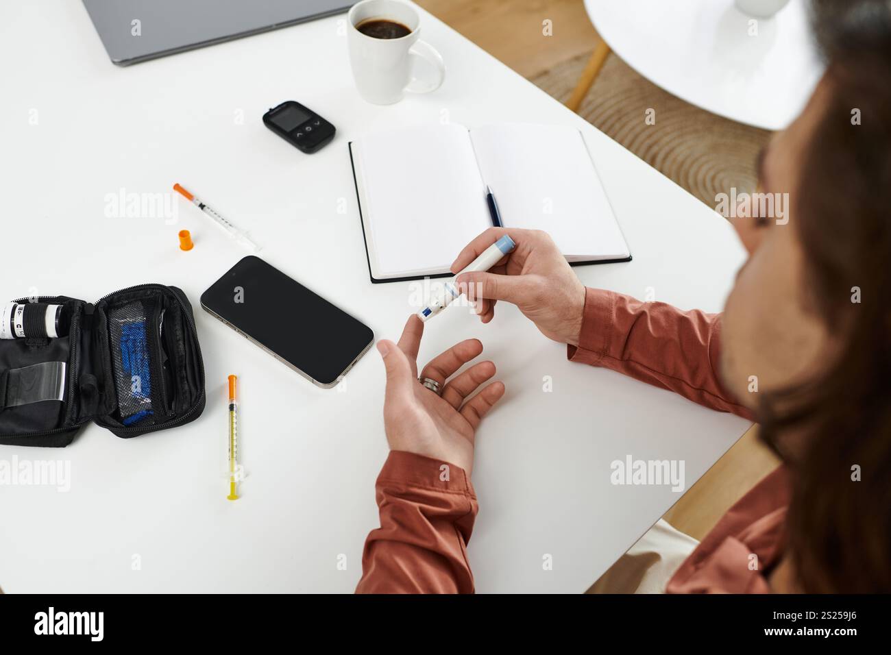 A young man with diabetes prepares his insulin while enjoying his daily ...