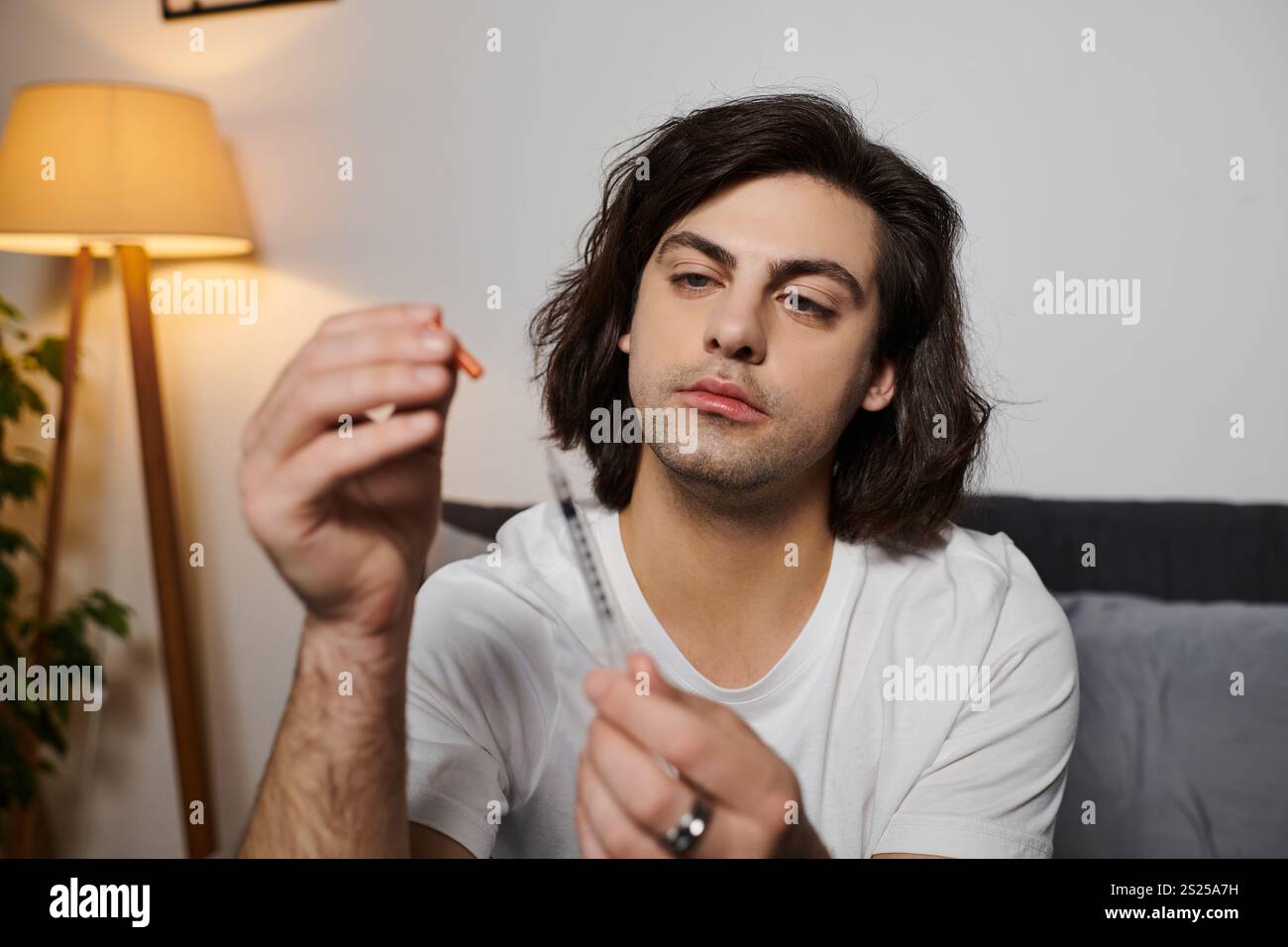A young man with diabetes carefully measures insulin at home ...