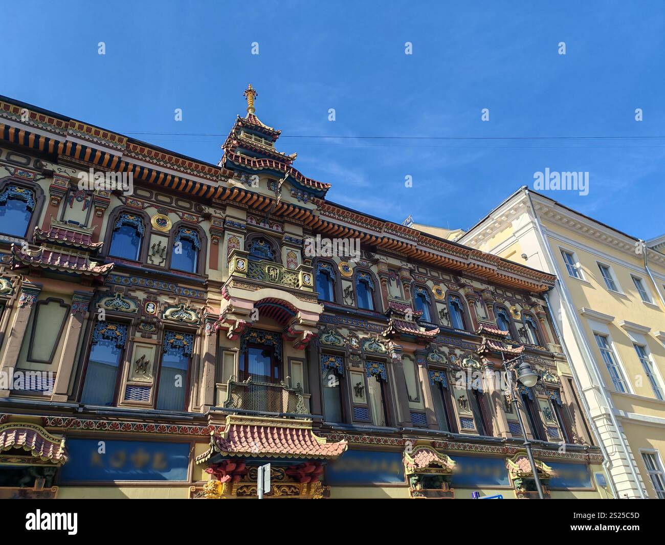 A three-story building with a pale yellow exterior and symmetrical ...