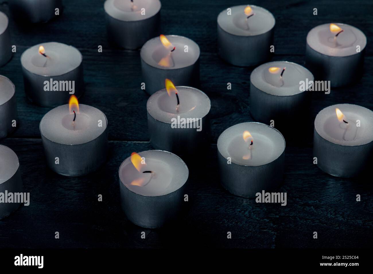 Tea light candles on a dark background, many lights in the dark ...