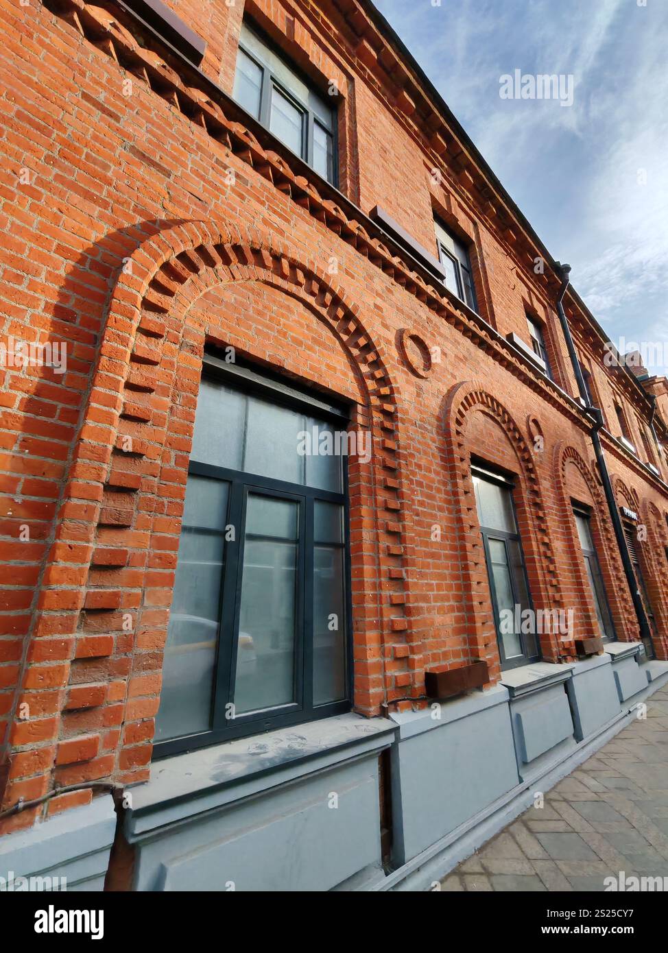 A vibrant red brick wall with arched window frames and decorative brick ...