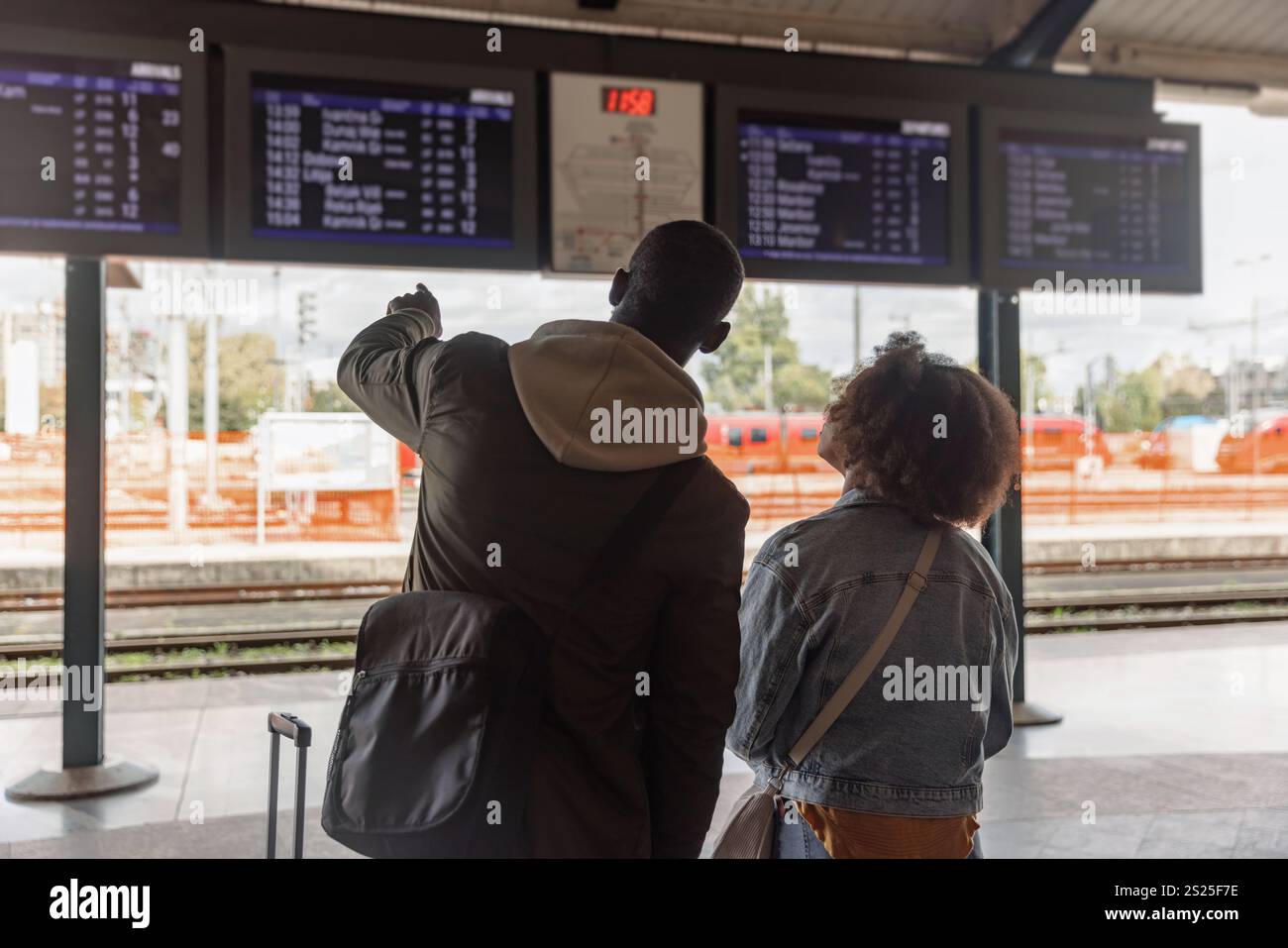 African American couple checking timetable arrival departure board on a ...